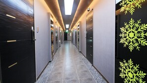 Um corredor de hotel com layout longo e reto, várias portas e chão de azulejos.