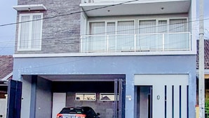 Uma casa de dois andares com garagem, uma varanda e um carro estacionado na garagem.