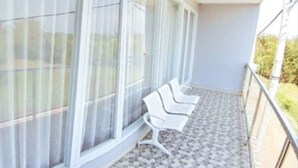 Uma varanda com cadeiras brancas e vista para um jardim.