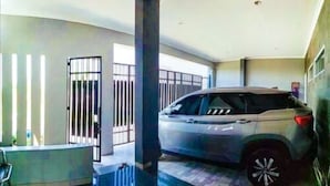 Interior moderno com um SUV estacionado, um pilar grande e uma entrada com portão.
