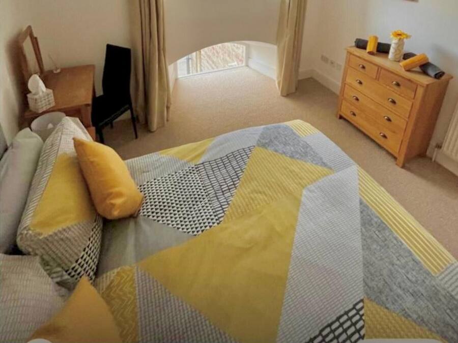 Quarto com cama, penteadeira, janela com cortinas e uma cadeira.