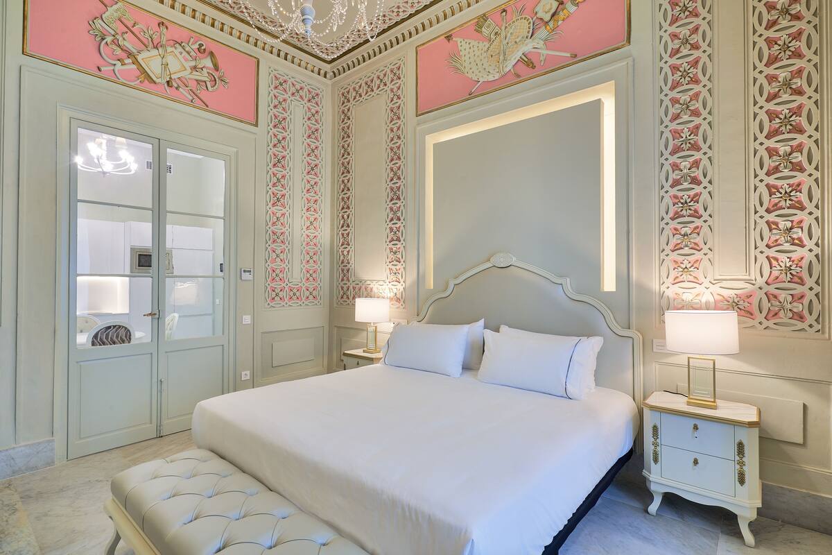Um quarto com uma cama grande, duas mesas de cabeceira, um espelho e um guarda-roupa.