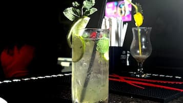 Um cocktail com rodela de limão e folhas de hortelã sobre um balcão de bar.