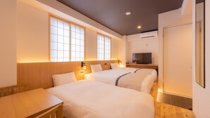 Quarto de hotel com duas camas, uma mesa de madeira e uma televisão.