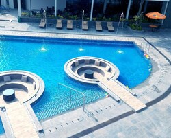 Uma piscina com área de estar circular, espreguiçadeiras e uma pequena mesa.