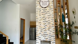 Uma cozinha moderna com painel de pedra, prateleira embutida de madeira e geladeira.