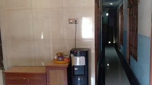Uma pequena cozinha compacta com geladeira, um armário de madeira e bancada com dispenser de água.