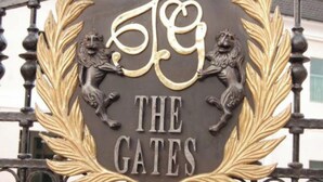 Um sinal com o texto 'THE GATES' rodeado por detalhes decorativos.