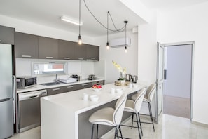 Cozinha moderna com ilha central, eletrodomésticos de aço inoxidável e iluminação pendente.