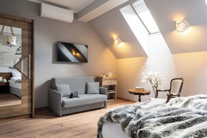 Quarto moderno com teto estilo loft, sofá, poltrona, mesinha com um vaso e cama com manta de pele.
