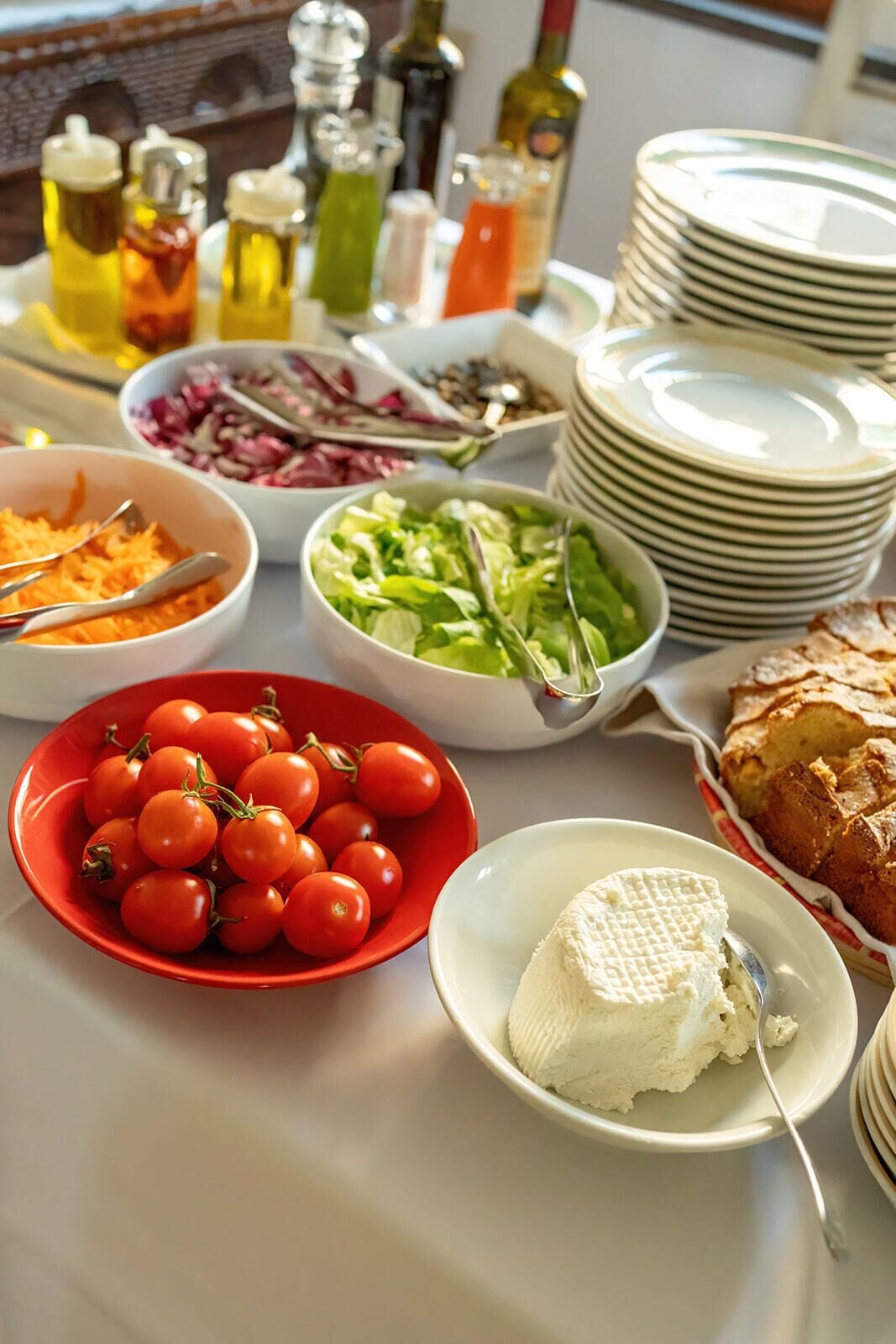 Uma mesa com diversos alimentos, incluindo uma tigela de tomates cereja, uma salada e um prato de queijo.