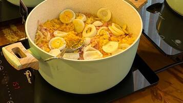 Disposição de buffet com diversos pratos, incluindo um caldeirão grande de arroz com ovos, um pote de chili e uma vitrine com doces.
