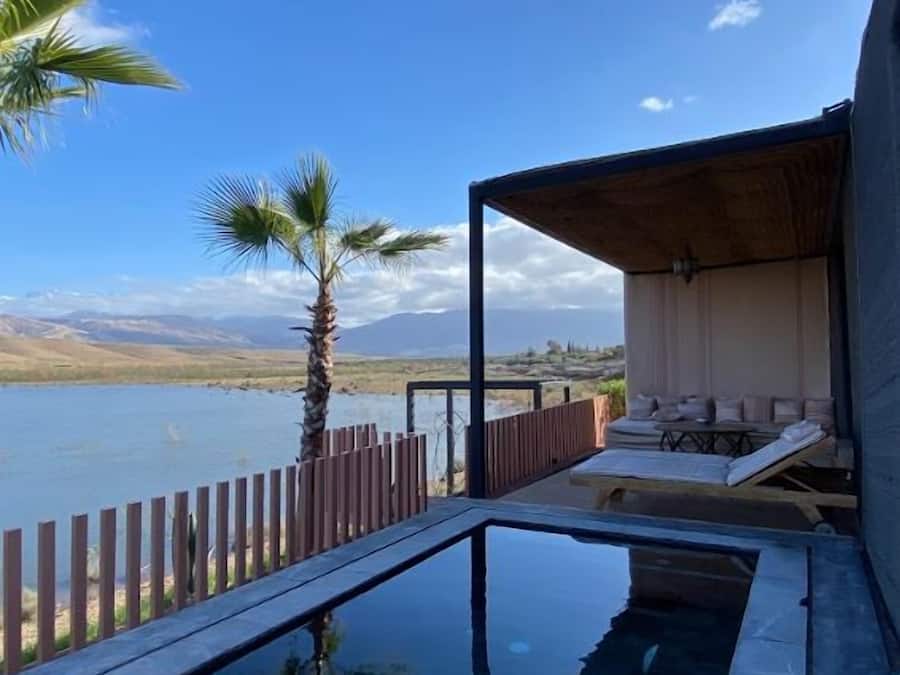 Uma piscina com deck de madeira, espreguiçadeiras e vista para a paisagem.