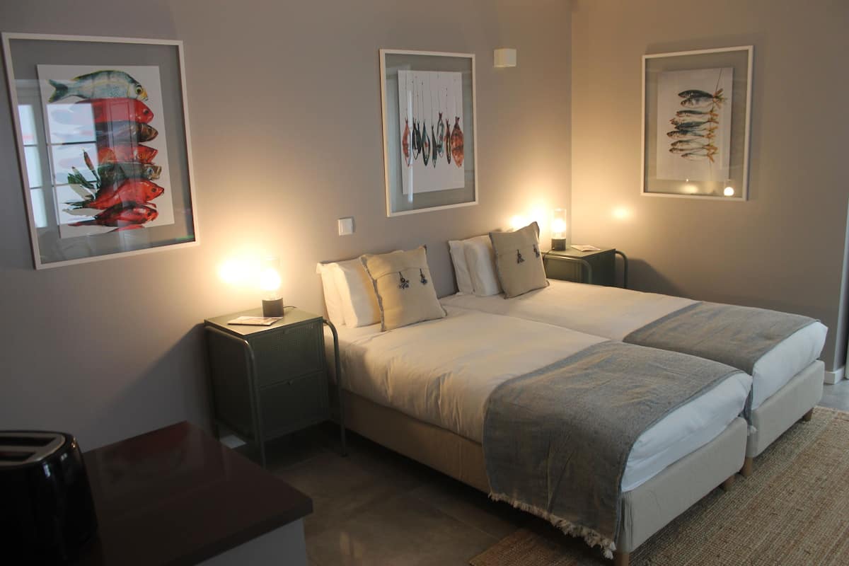 Quarto com cama de casal, duas mesas de cabeceira e quadros nas paredes.