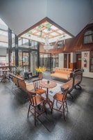 Um espaço interno amplo com mobiliário de madeira, uma área de estar central e entrada por porta de vidro.