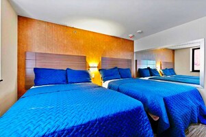 Quarto de hotel com duas camas, cabeceiras de madeira e um espelho grande numa parede.
