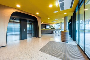 Um hall moderno com piso texturizado, um balcão de recepção e um painel de vidro com vista externa.