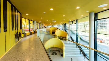 Um interior moderno com esquema de cores amarelo, guarda-corpos de vidro e escada que leva a um andar superior.