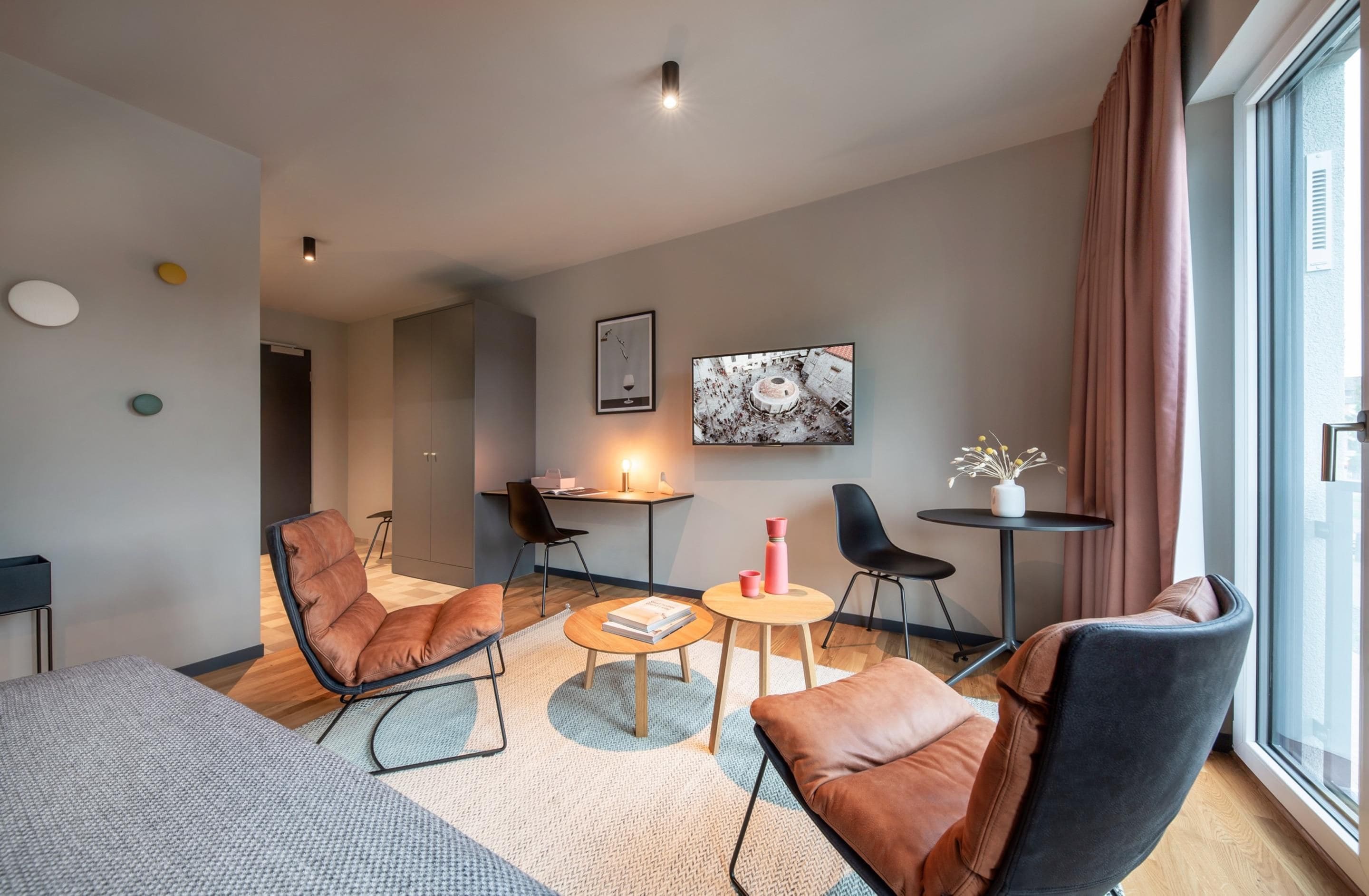 Uma sala de estar moderna com sofá, cadeiras, mesa de centro e televisão.