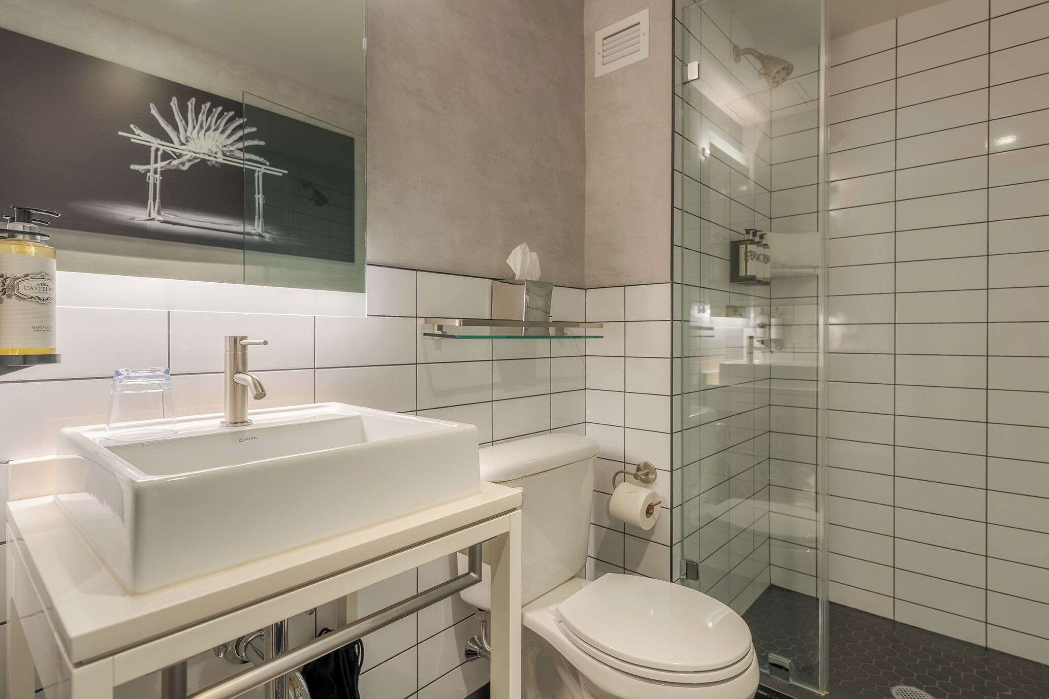 Casa de banho moderna com lavatório branco, sanita e cabine de duche em vidro.