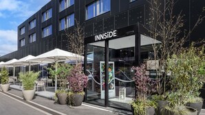 A modern building with the sign "INNSIDE" and outdoor seating with umbrellas.