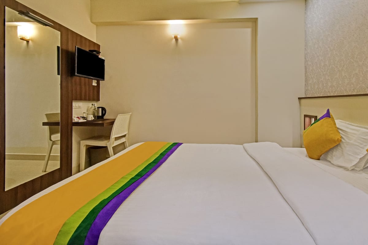 Quarto de hotel com cama, secretária e uma cadeira.