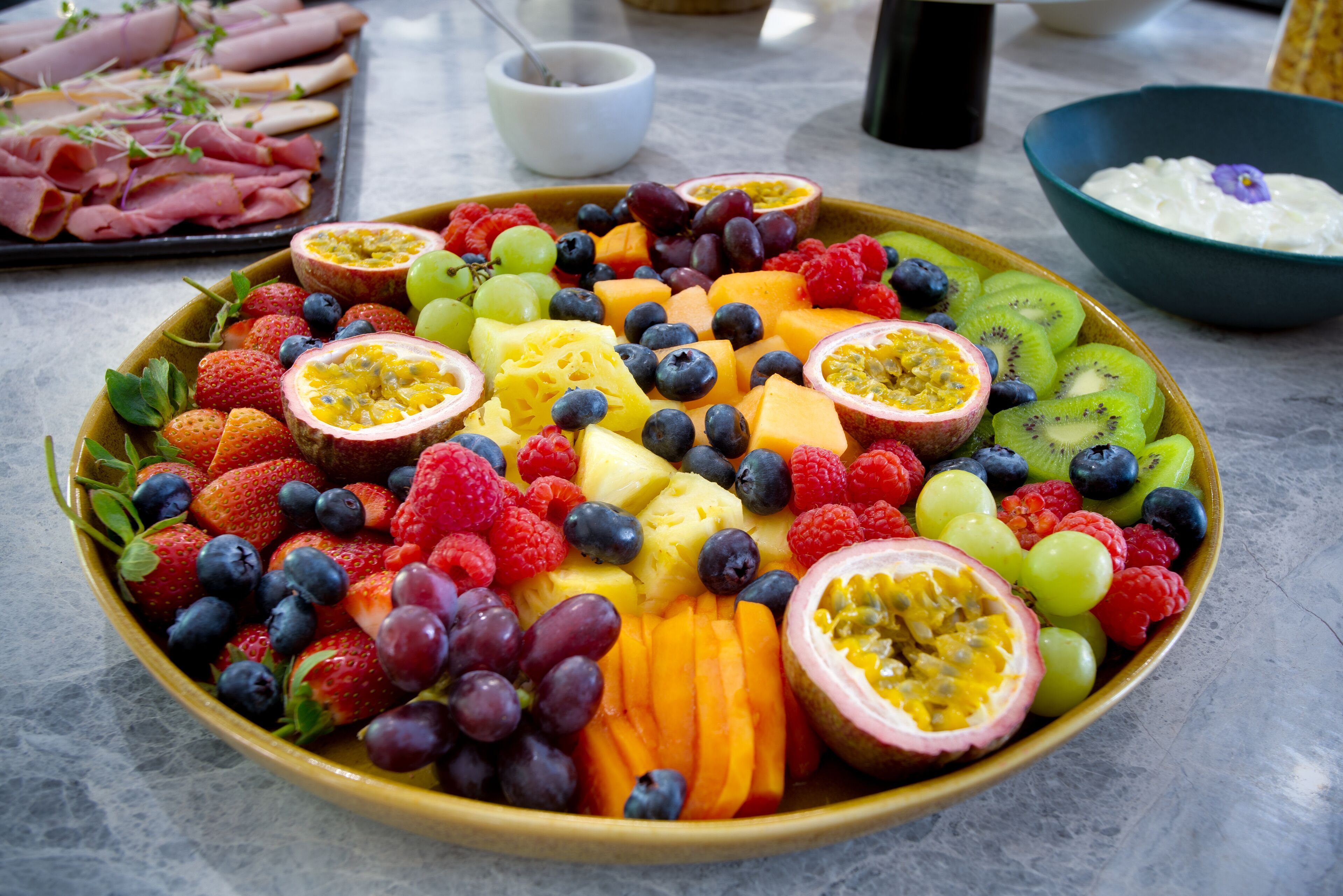 Um prato de frutas variadas e uma tigela de iogurte.