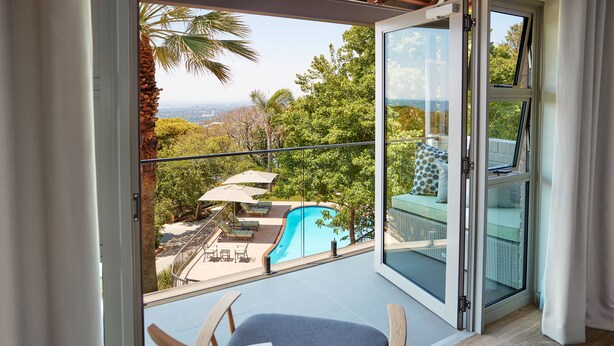 Uma varanda com vista para uma piscina, móveis de exterior e vegetação exuberante.