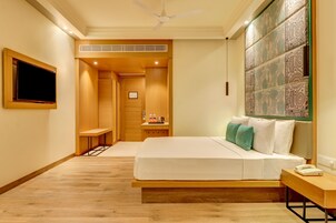 Quarto moderno com cama, mesa de cabeceira e televisão na parede.