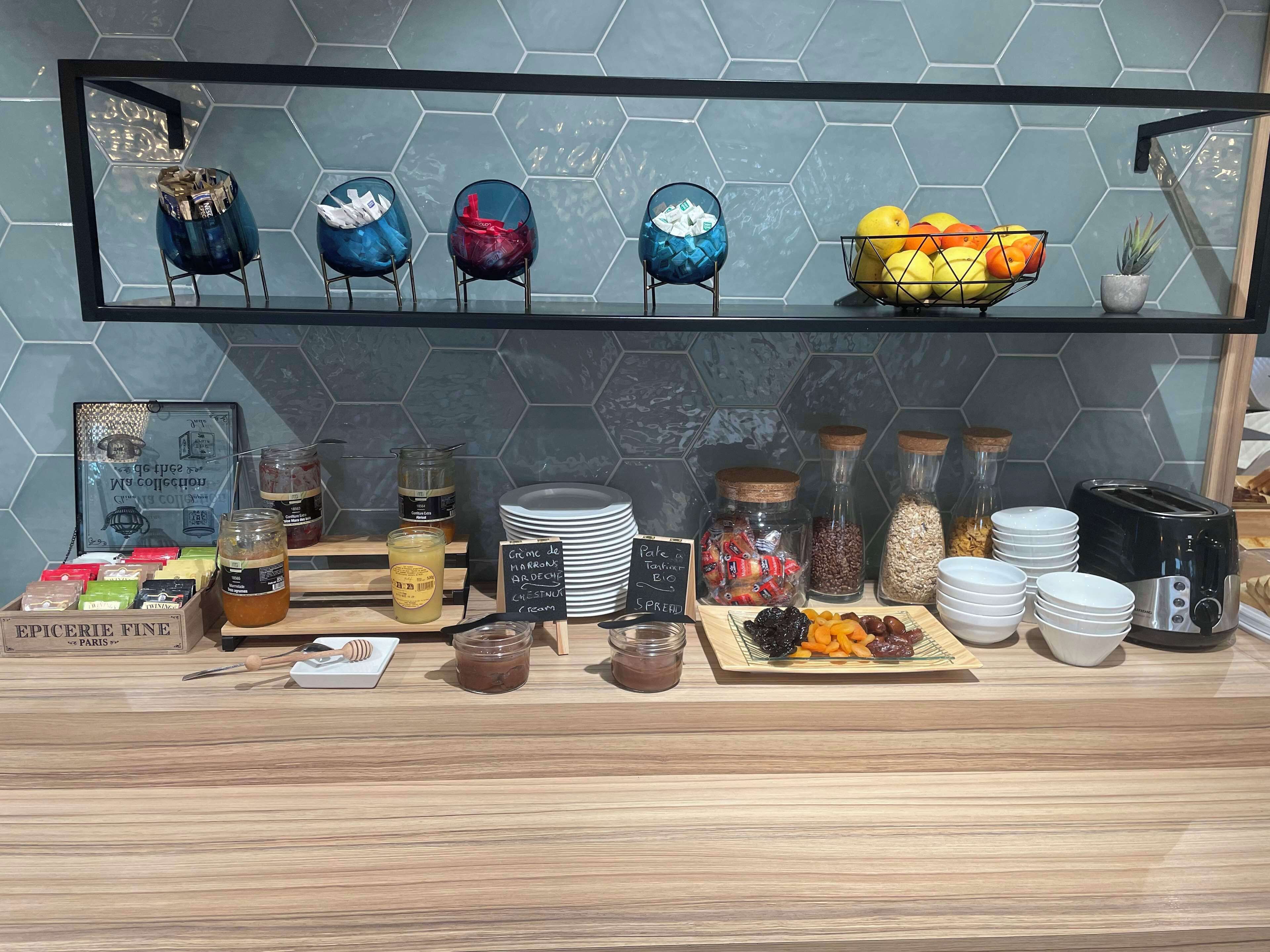 Buffet de café da manhã com diversos alimentos, potes de patês e uma torradeira.