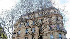 Um edifício de vários andares com arquitetura clássica, com varandas e grandes janelas.
