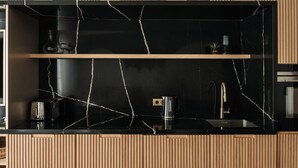 Uma cozinha moderna com bancadas de mármore preto, armários de madeira e pia de aço inoxidável.