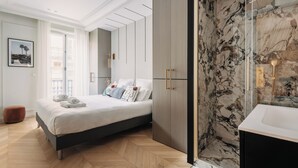 Um quarto moderno com uma cama grande, um closet espaçoso e um chuveiro em mármore.