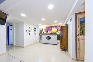 Uma área de recepção com balcão, relógio e porta numerada.