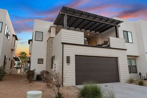 Uma casa moderna de dois andares com garagem, varanda e pérgola.