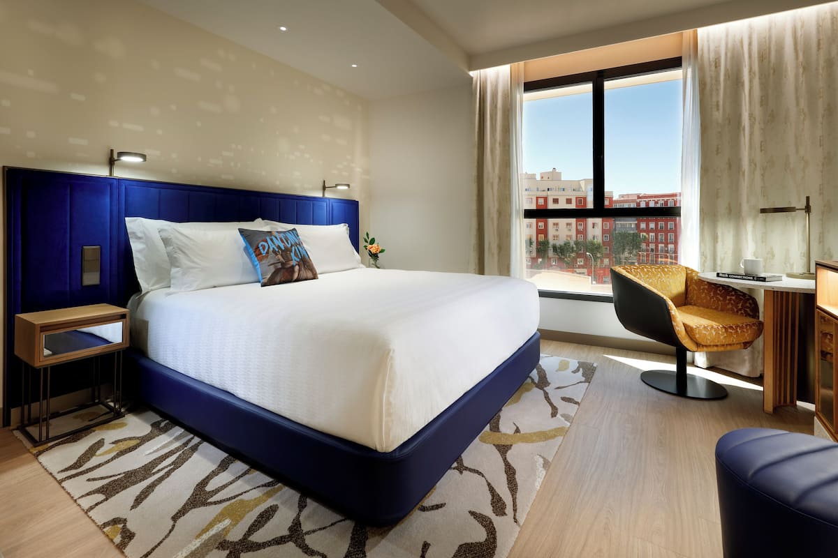 Quarto de hotel moderno com uma cama grande, uma escrivaninha e vista para edifícios.