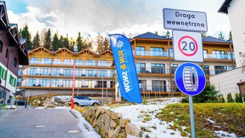 Um hotel com uma placa indicando limite de velocidade de 20 km/h e uma faixa azul com o texto "Sun & Snow".
