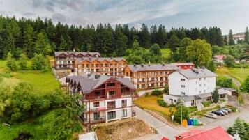 Um hotel com vários andares, que combina arquitetura moderna e tradicional, cercado por vegetação exuberante e uma área arborizada.