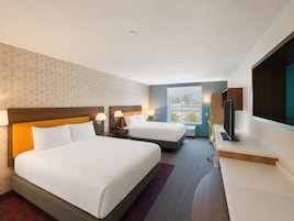 Quarto de hotel com duas camas, uma escrivaninha, televisão e janela com vista.
