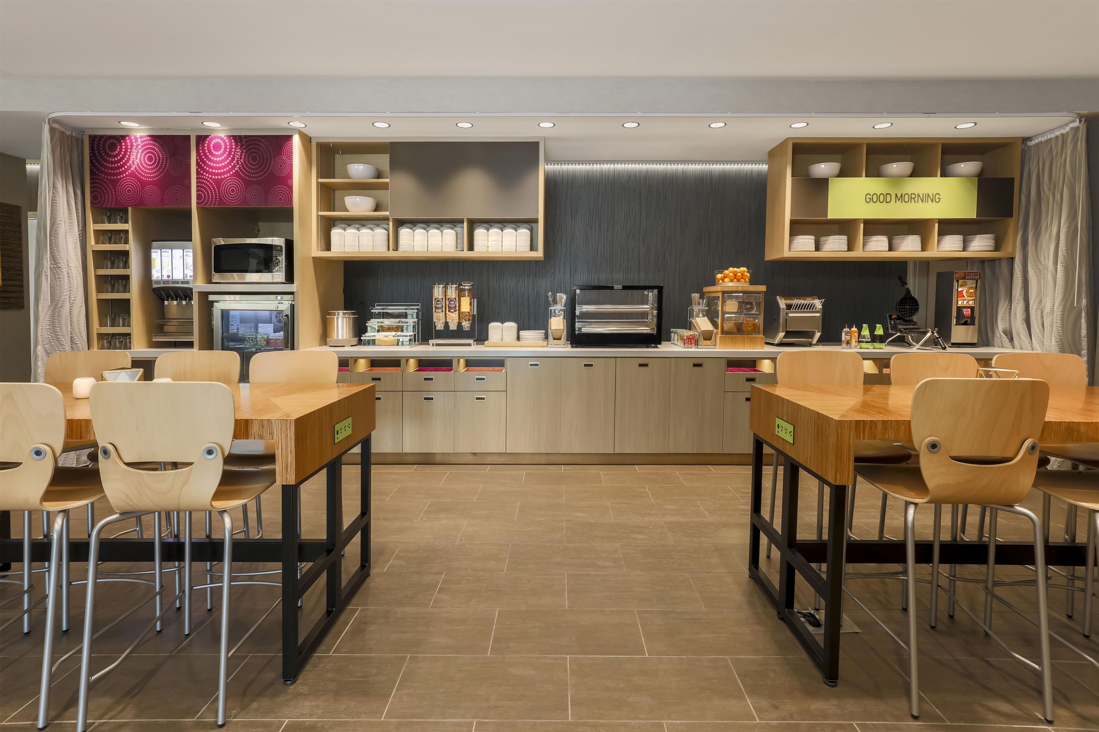 Um café moderno com ilha central, área de estar e balcão de cozinha.
