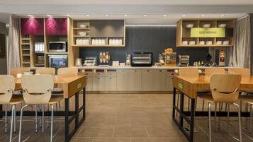 Um café moderno com ilha central, área de estar e balcão de cozinha.