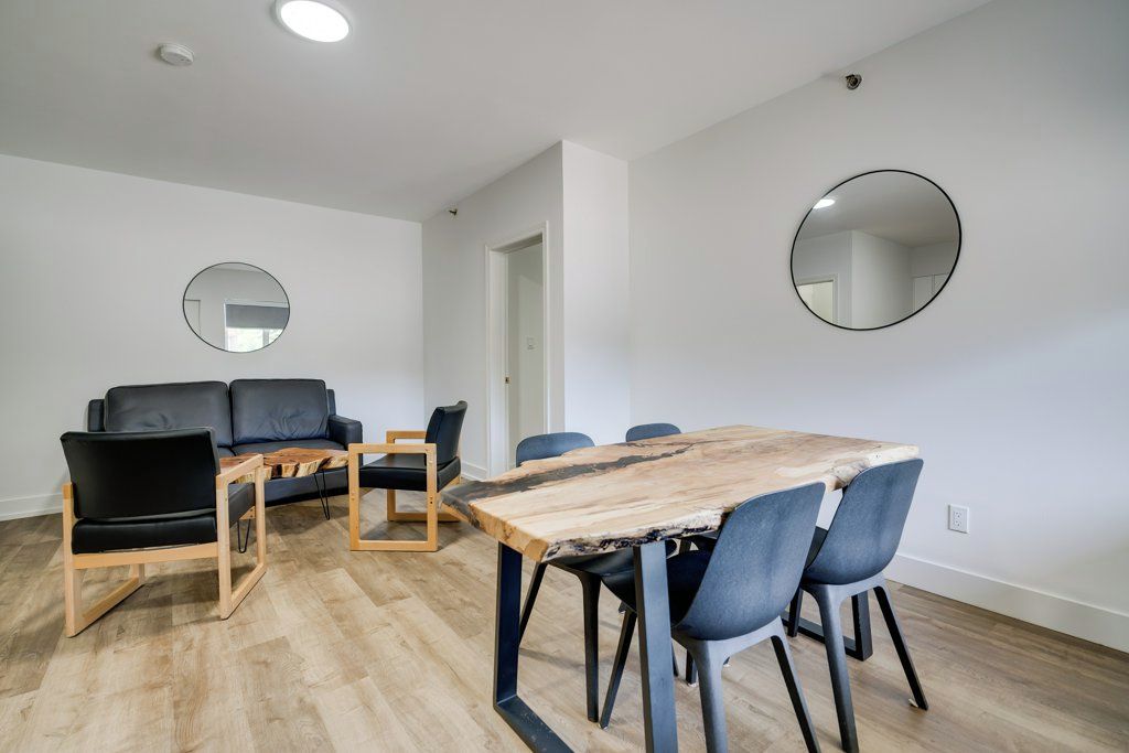 Uma sala de estar moderna com um sofá, cadeiras, uma mesa de centro e uma mesa de jantar.