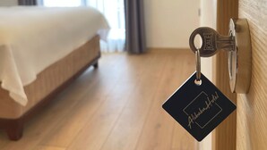 Quarto de hotel com uma cama, uma porta com chave e uma etiqueta com a inscrição 'Alibaba Hotel'.