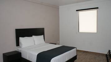 Quarto com cama, mesa de cabeceira, janela e porta.