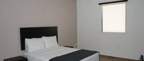 Quarto com cama, mesa de cabeceira, janela e porta.