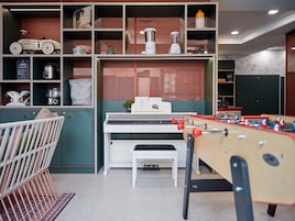 Quarto com mesa de pebolim, piano, berço e prateleira com diversos objetos.