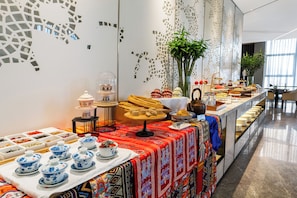 Disposição de buffet com diversos alimentos e uma parede decorativa.