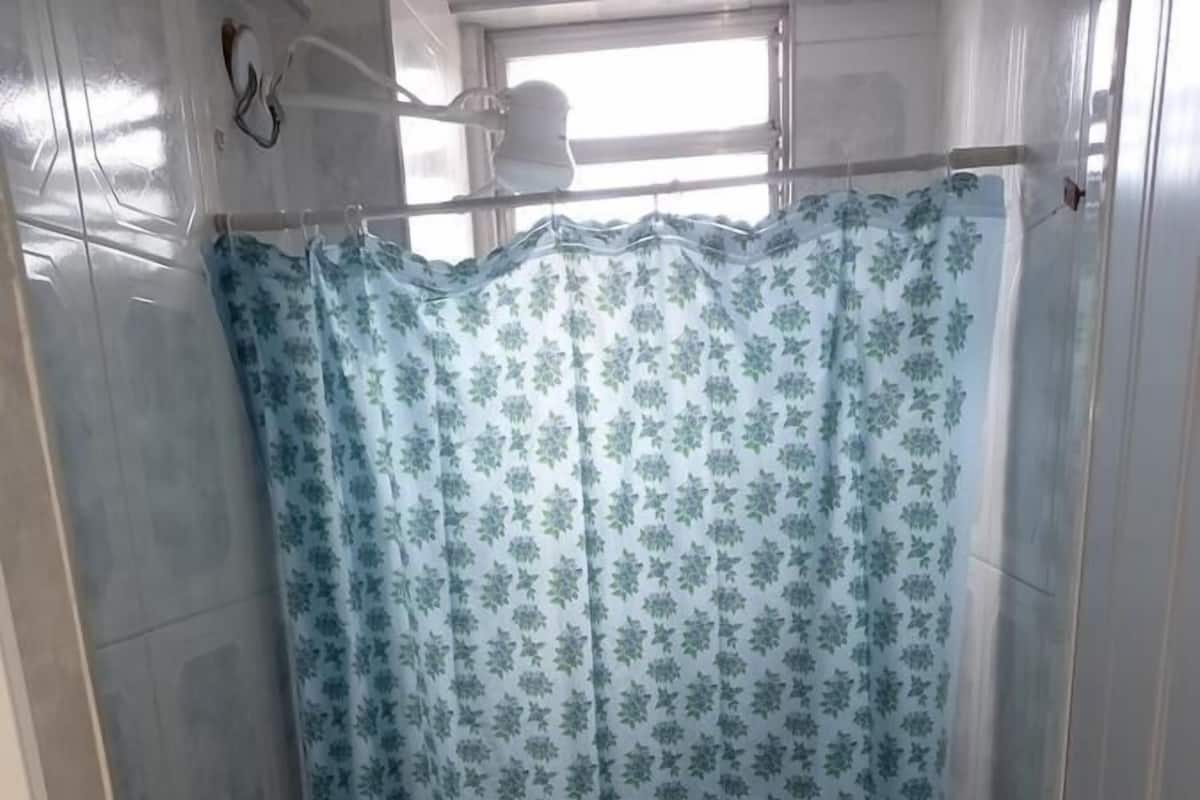 Uma casa de banho pequena com sanita, cortina de chuveiro e suporte para papel higiénico.