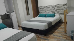 Quarto com duas camas, um guarda-roupa e uma escrivaninha.