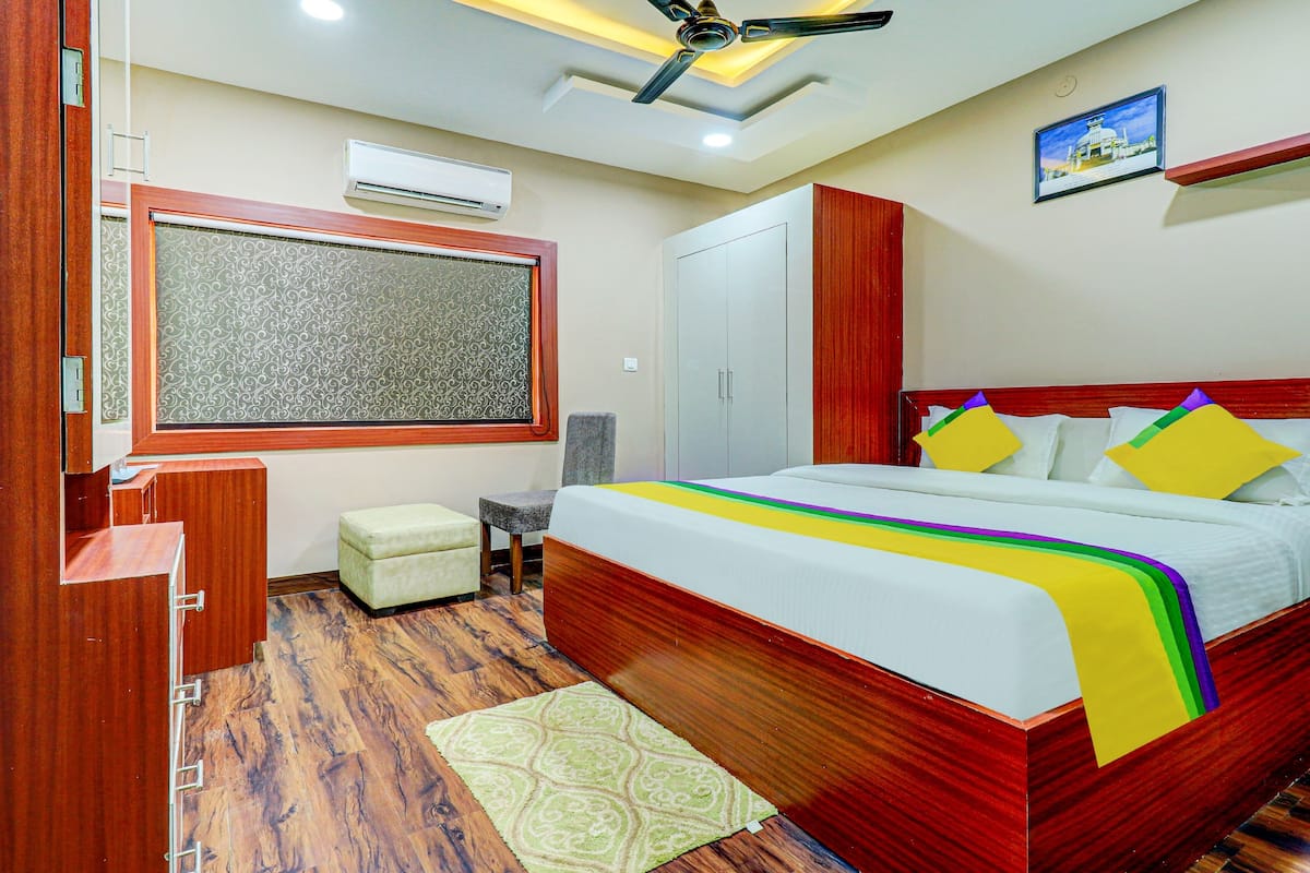 Quarto de hotel com cama de madeira, guarda-roupa, escrivaninha e cadeira.